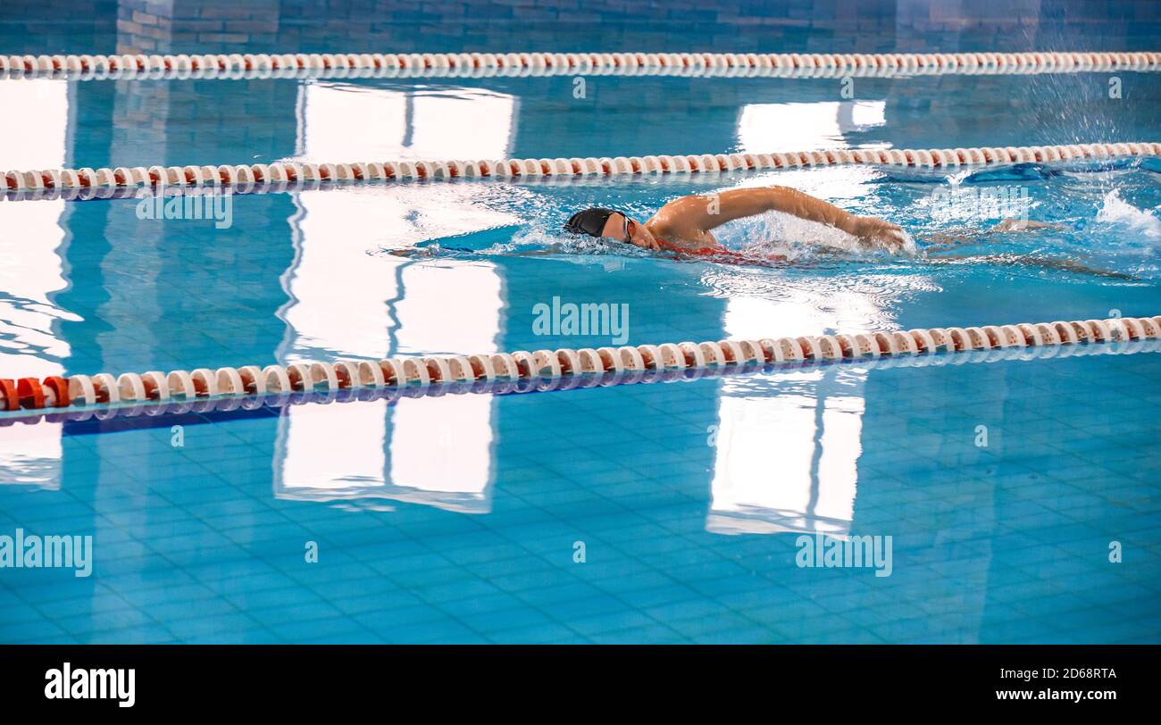 Young woman swimmer is swimming in the pool. Freestyle stroke, front ...