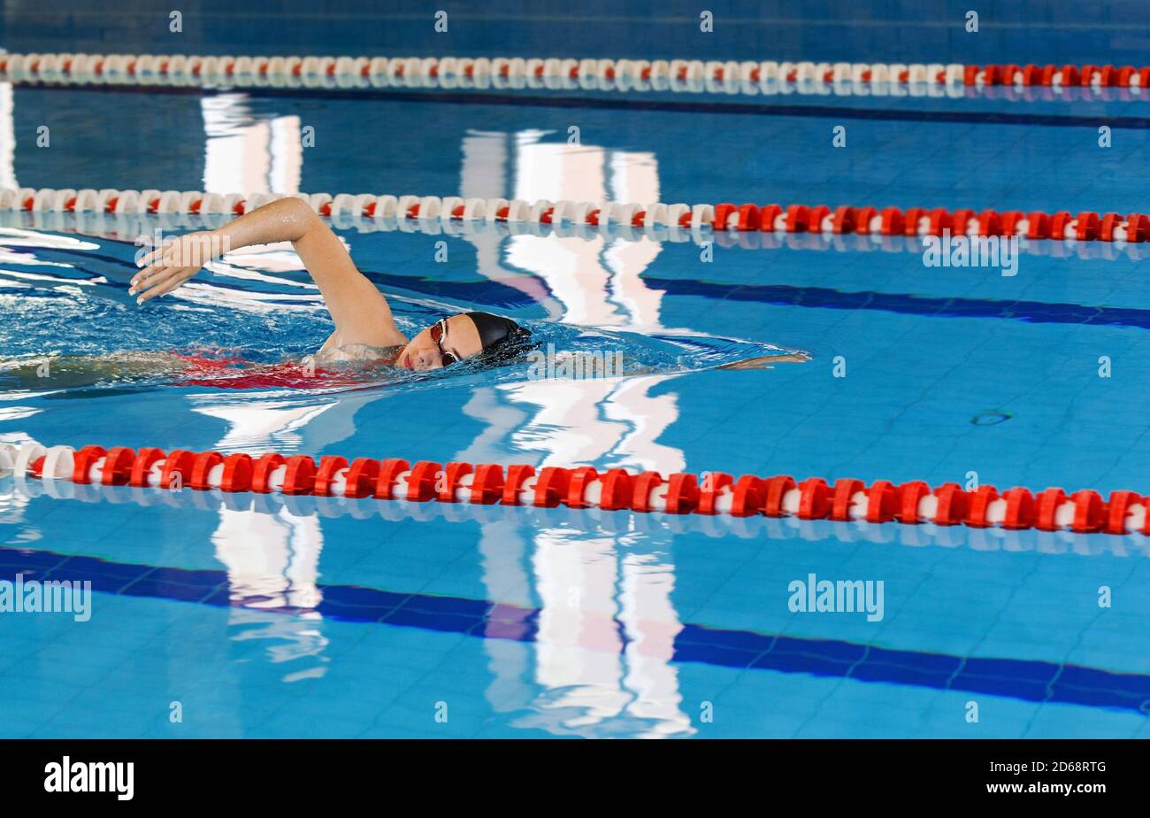 Young woman swimmer is swimming in the pool. Freestyle stroke, front ...