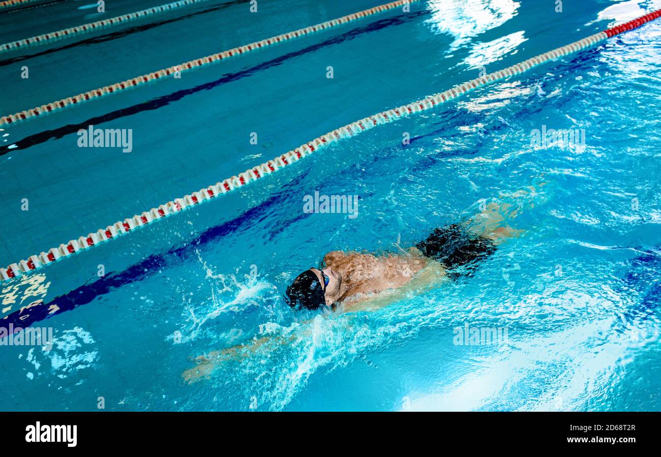 Man swimmer is swimming in the pool, backstroke technique swimming ...