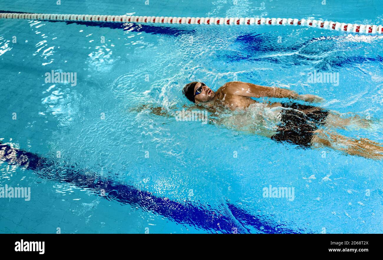 Man swimmer is swimming in the pool, backstroke technique swimming ...