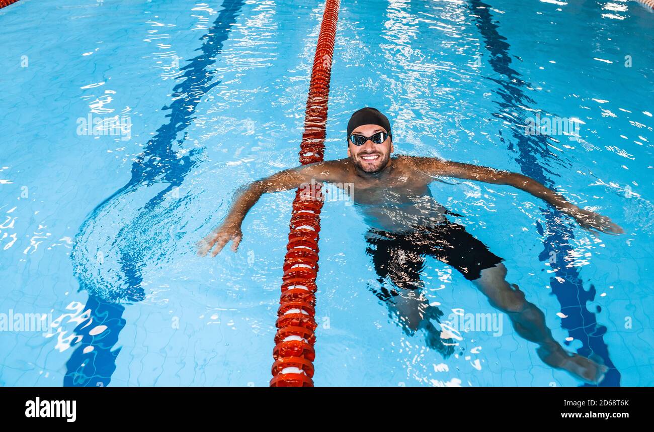 Portrait of a positive professional swimmer in a pool resting after ...