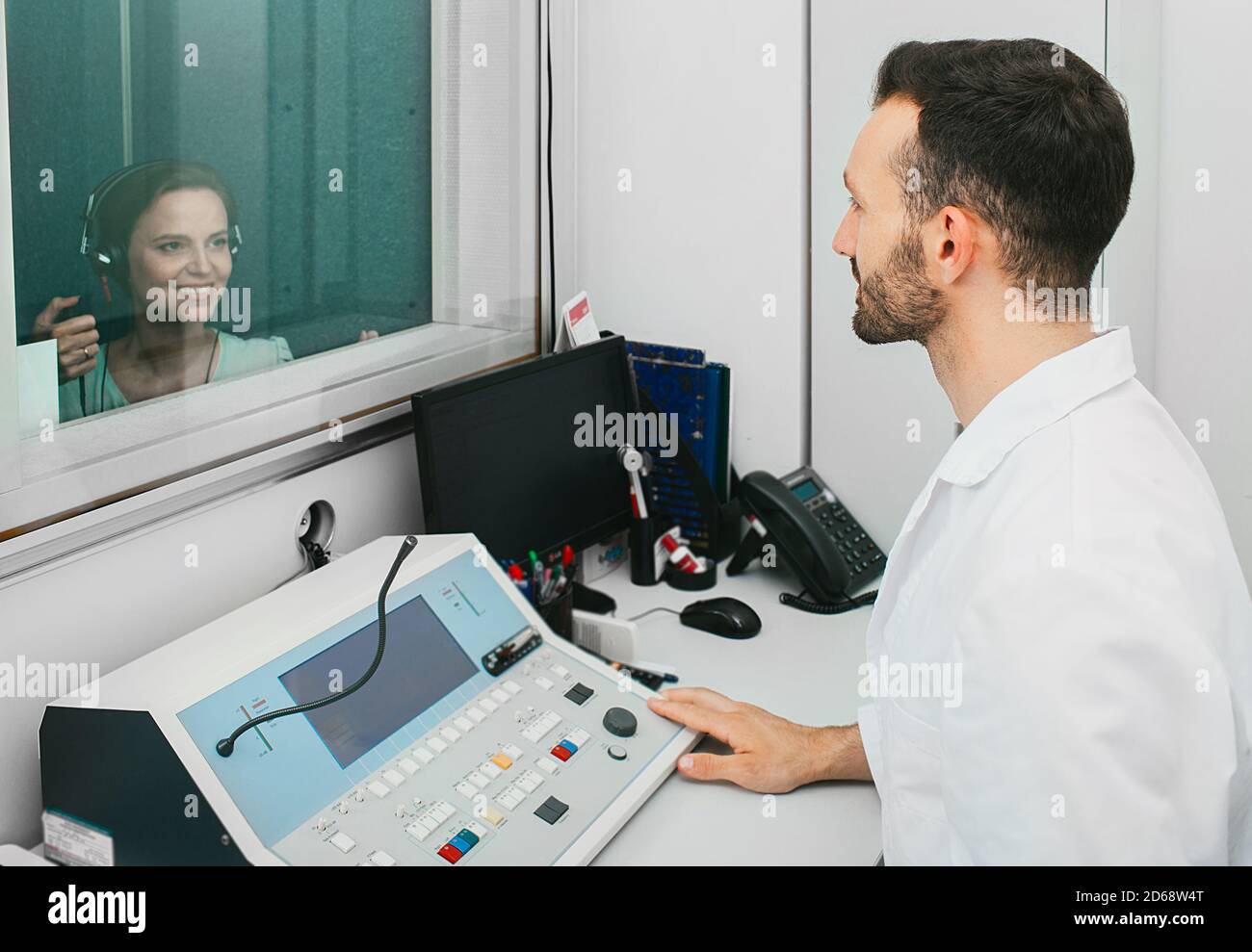Audiologist man doing the hearing exam to an adult woman patient using ...