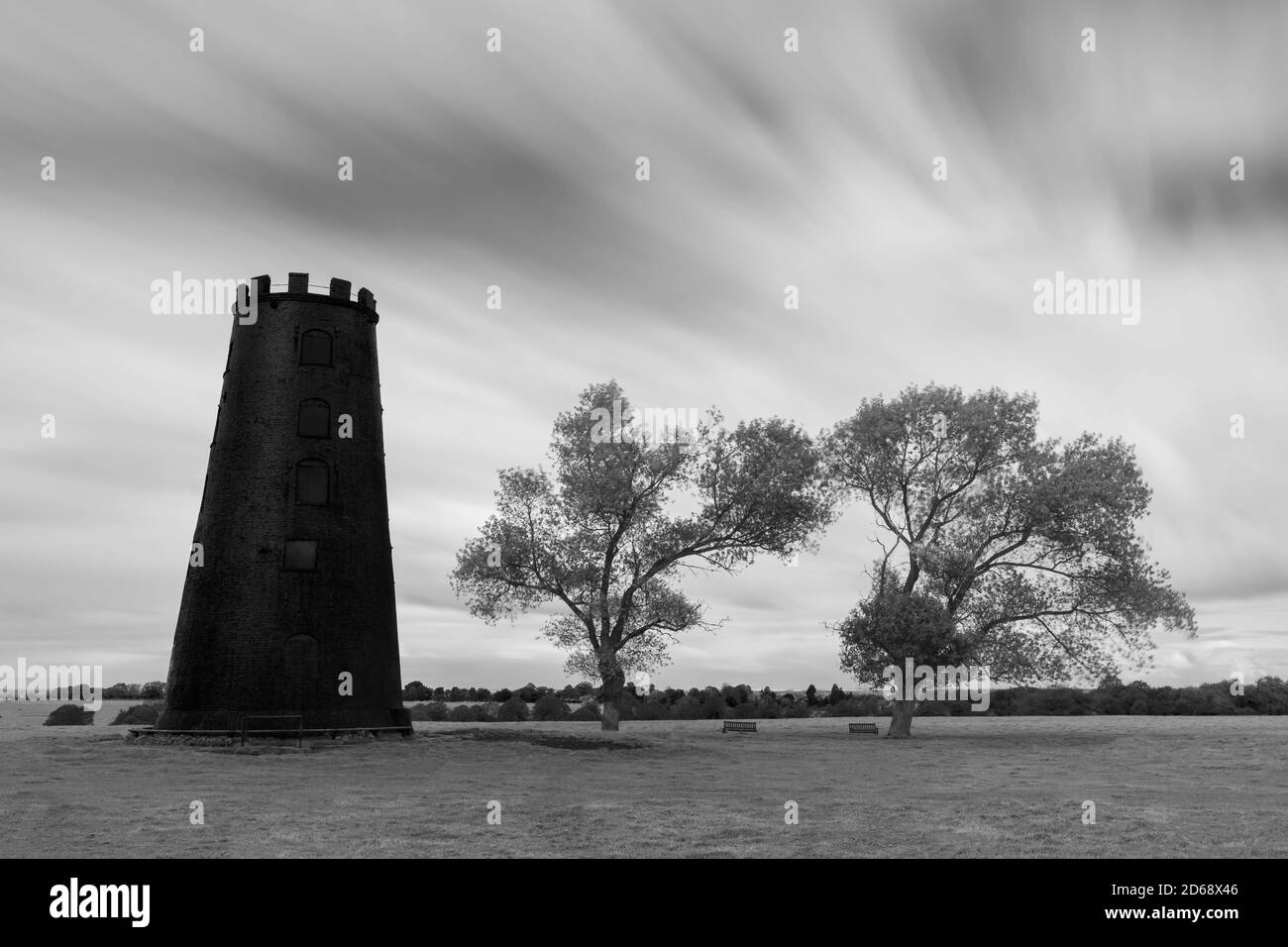 Long exposure of disused windmill in middle of open pasture on windy ...