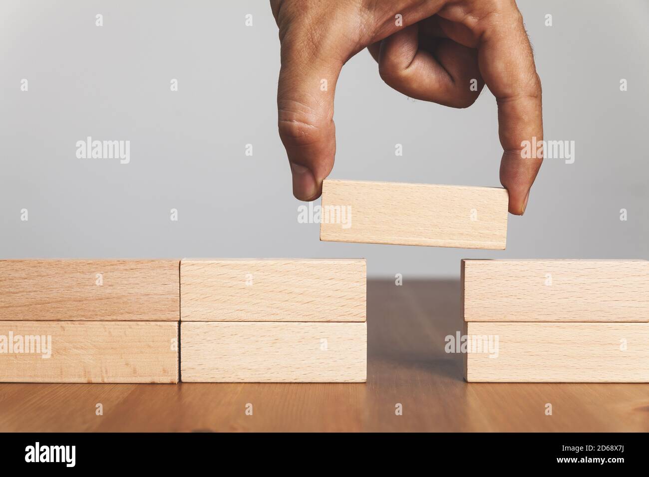 Human hand putting a wooden block on the pile of wooden blocks Stock ...