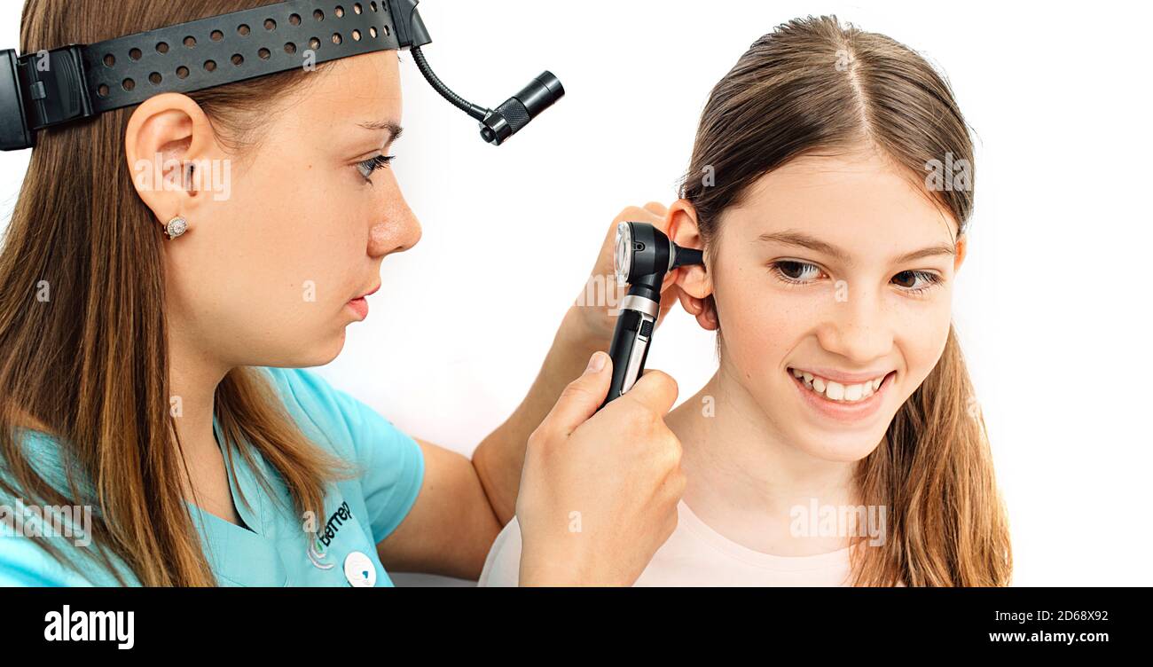 Girl patient getting ear exam at clinic, a doctor examining patient ear ...