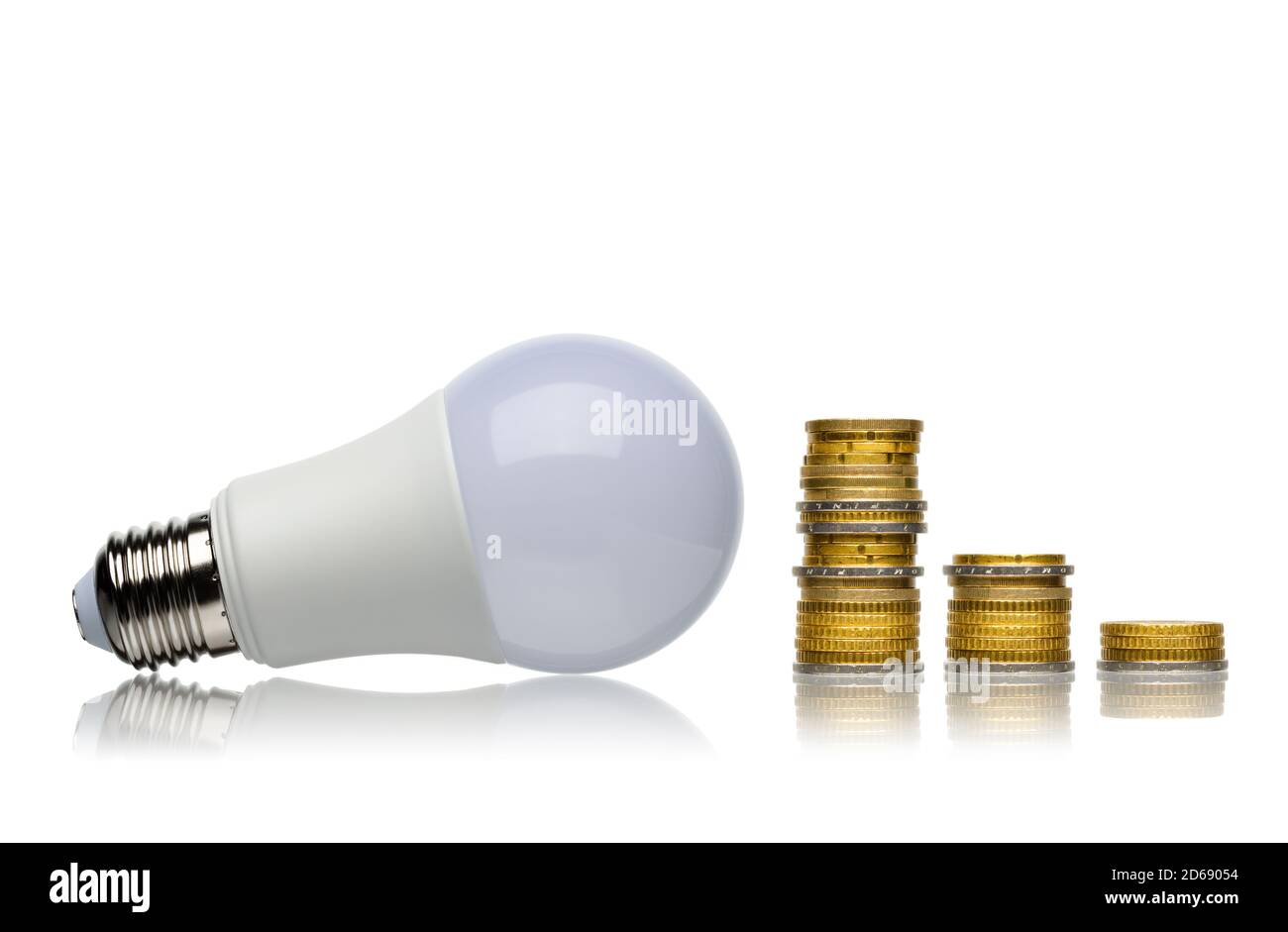 Energy saving lamp and column stack of coins isolated on white ...