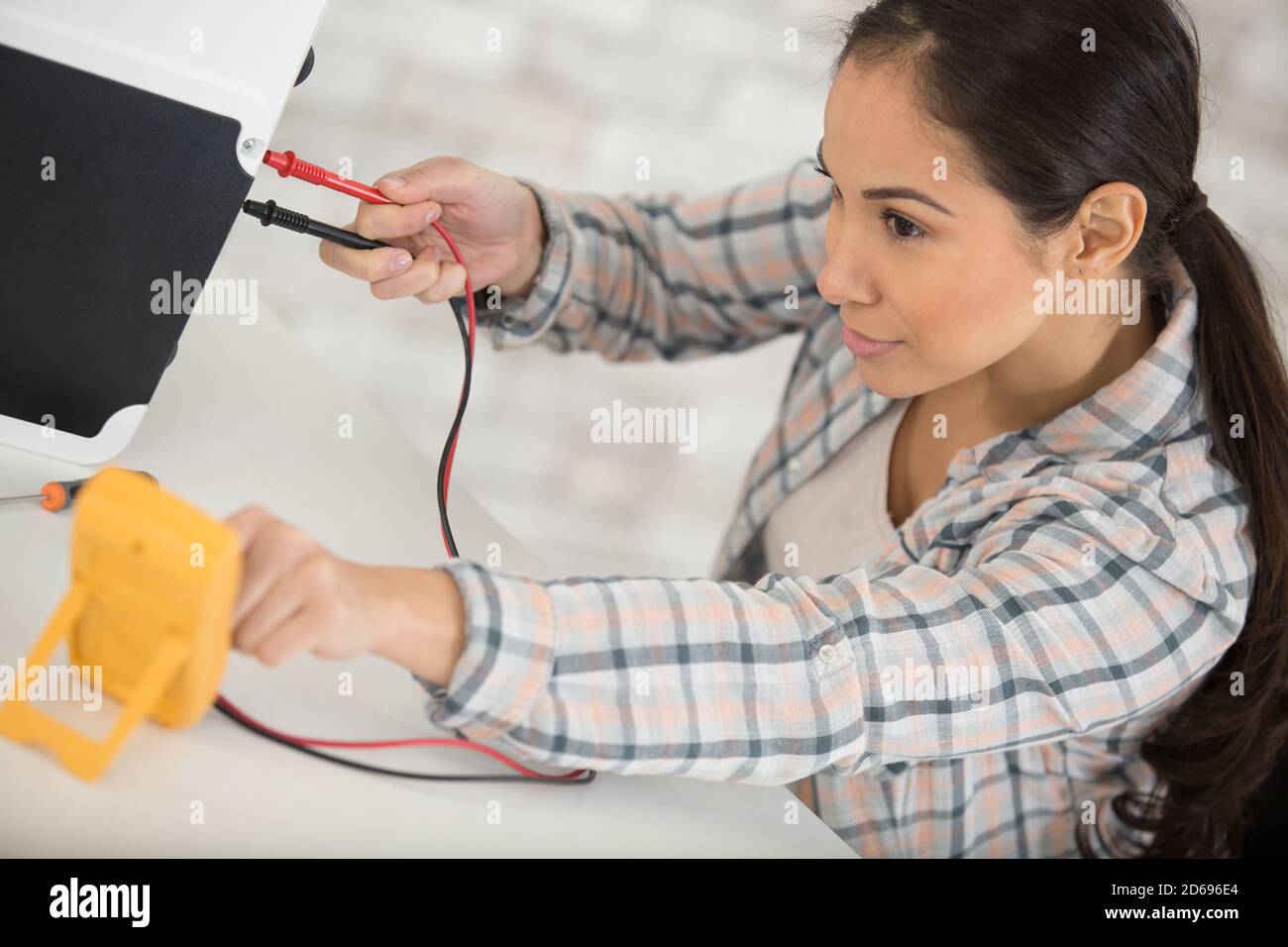 female technician testing appliance with multimeter Stock Photo - Alamy