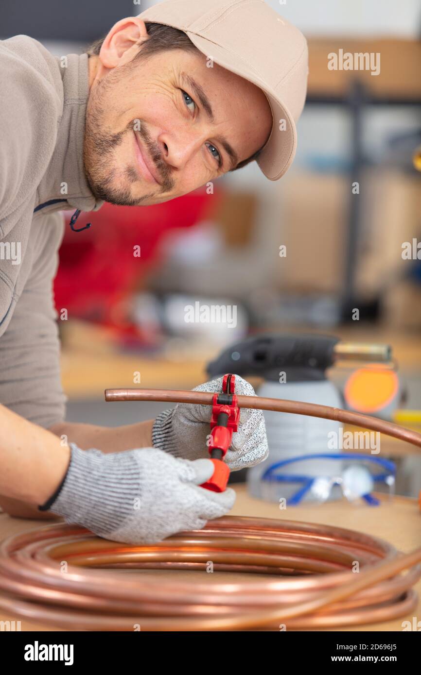 smiling workman cuts copper pipe using special tool Stock Photo - Alamy