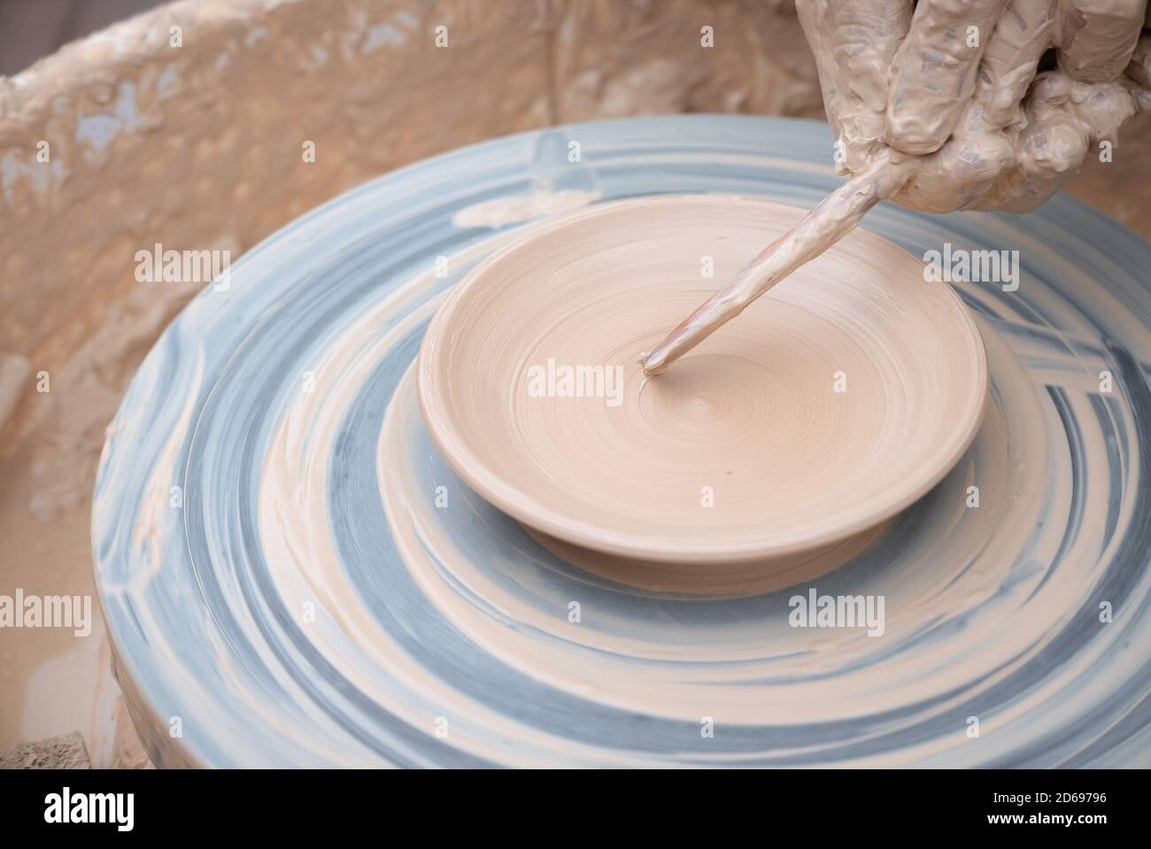 Clay plate rotating on the pottery wheel Stock Photo - Alamy