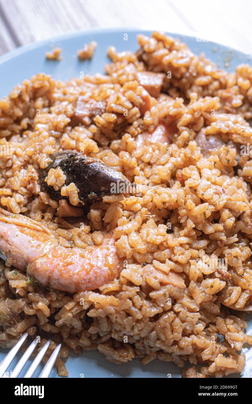 Paella yellow rice served with prawns and seafood on a blue plate Stock ...