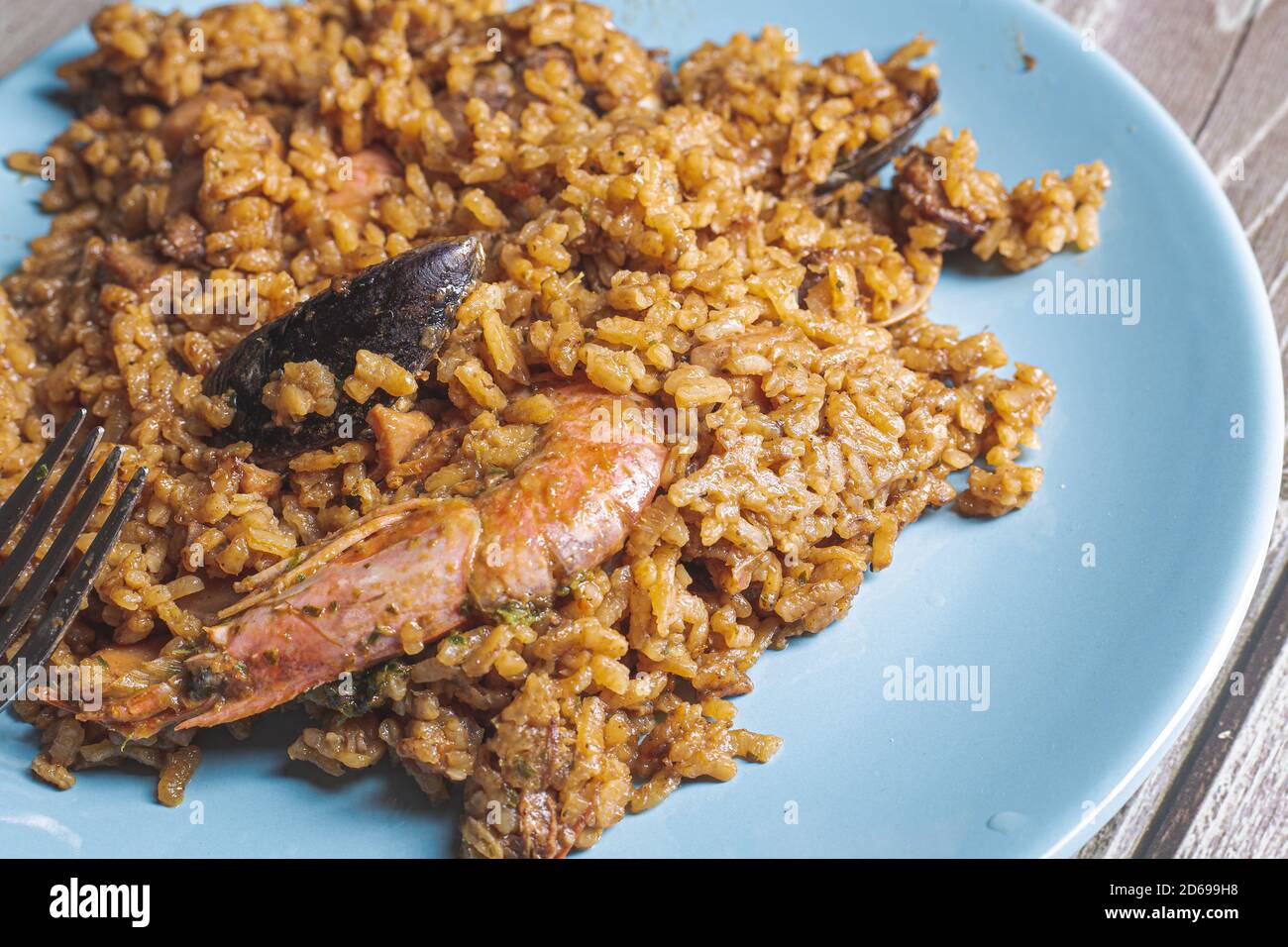Paella yellow rice served with prawns and seafood on a blue plate Stock ...
