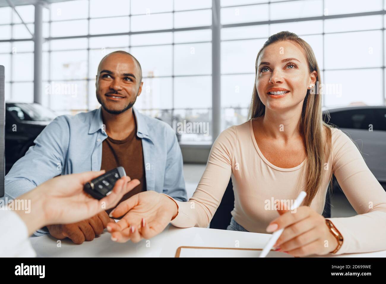 Beautiful young couple signs documents at car dealership showroom Stock ...
