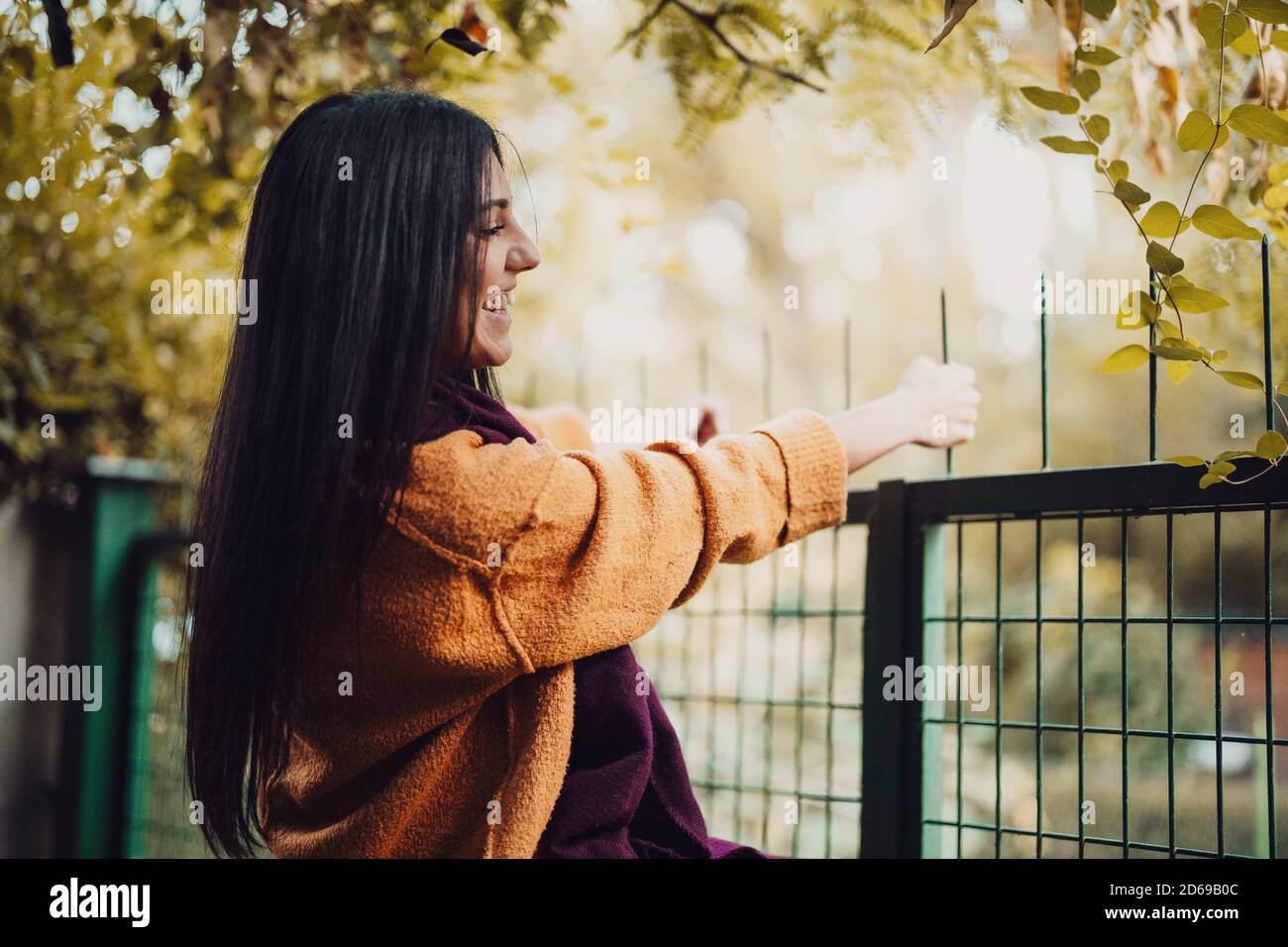 Woman looking through the metal fence in the forest Stock Photo - Alamy