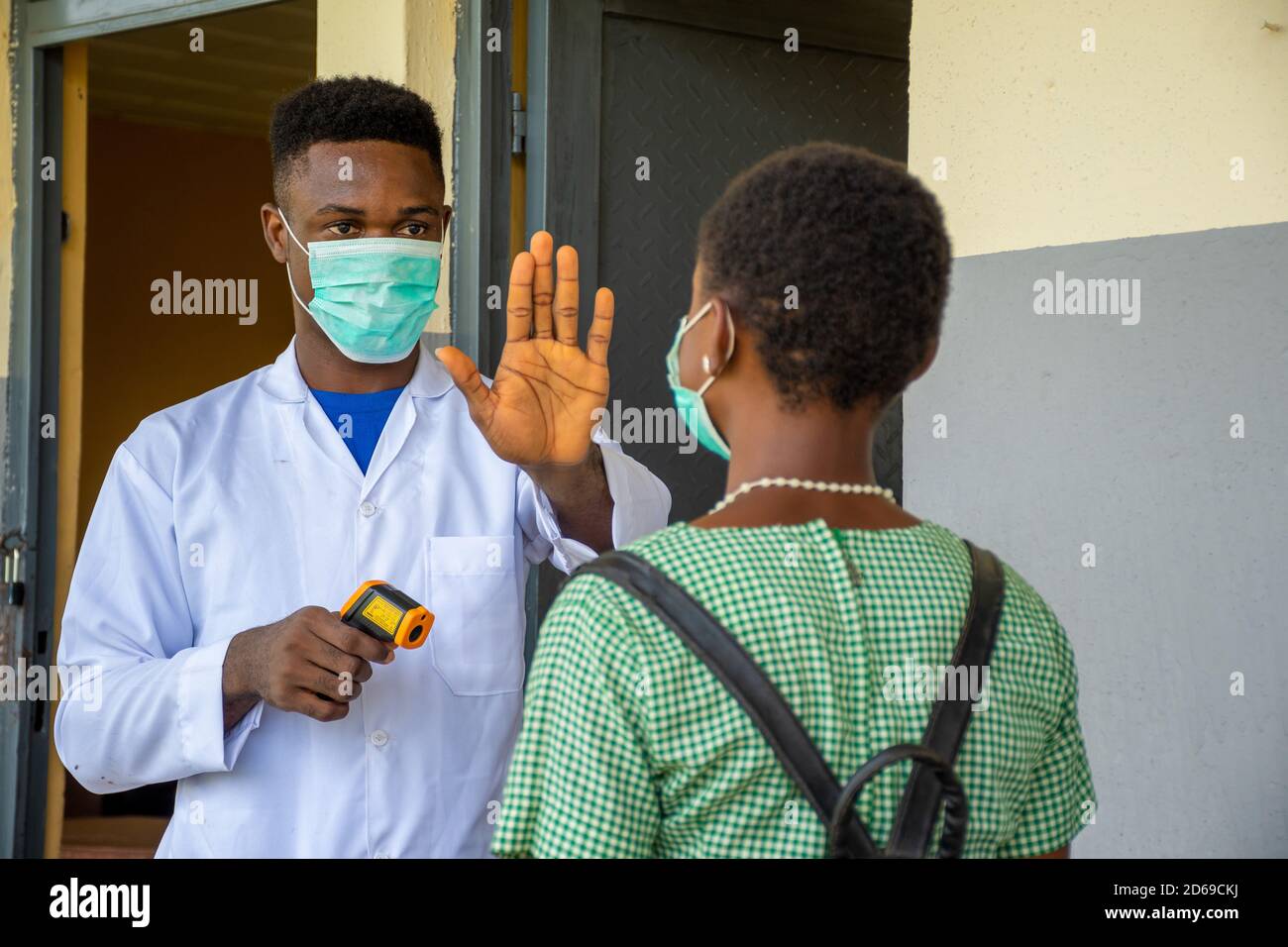 african school teacher stops a pupil for body temperature check before ...
