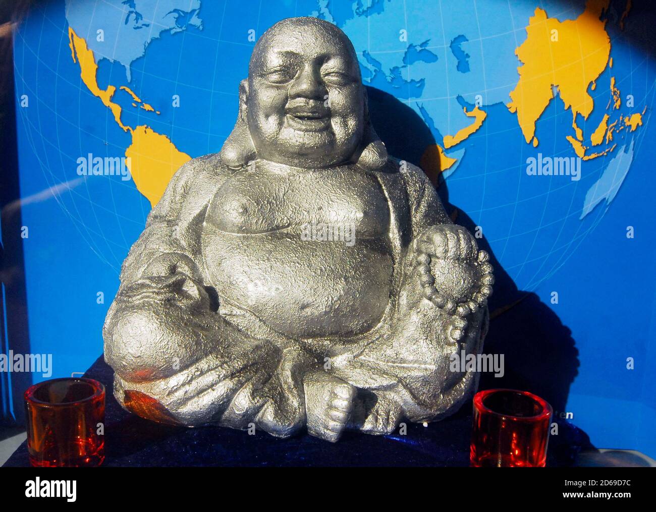 statue of laughing Buddha in front of blue world map Stock Photo - Alamy