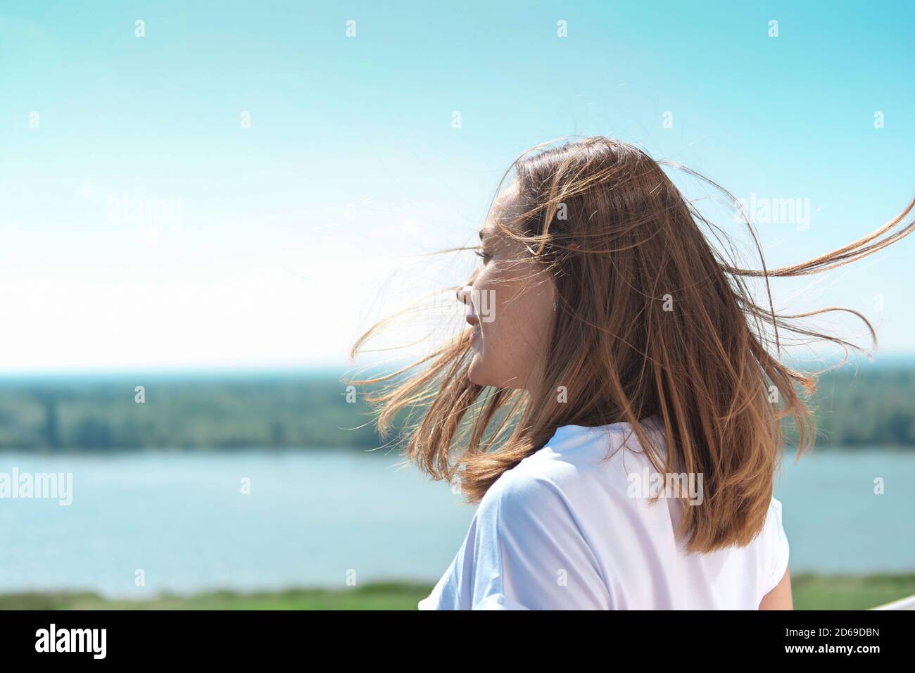 beautiful woman with messy hair blown by wind looking at landscape ...