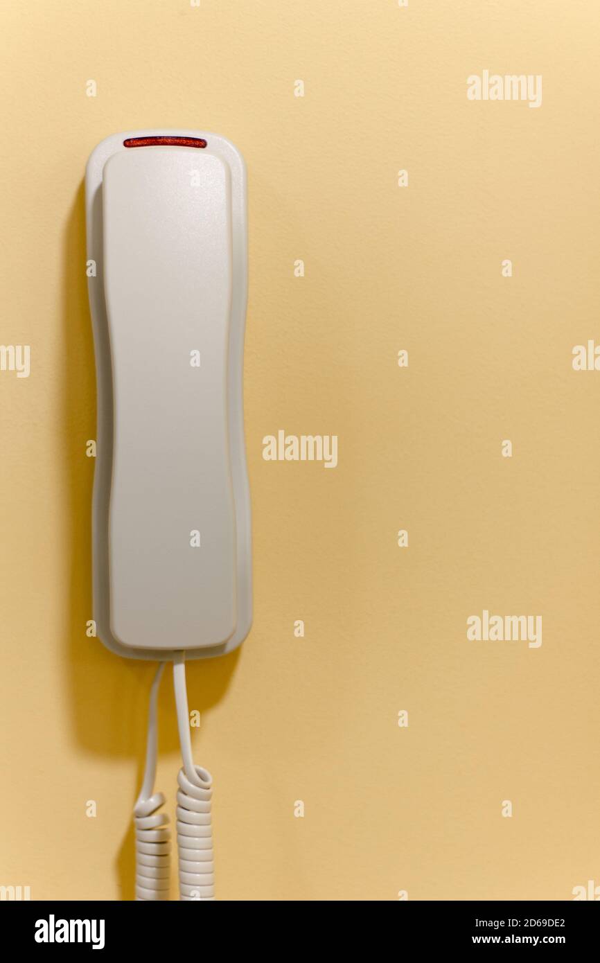 White plastic phone on a wall for emergency call or support Stock Photo ...