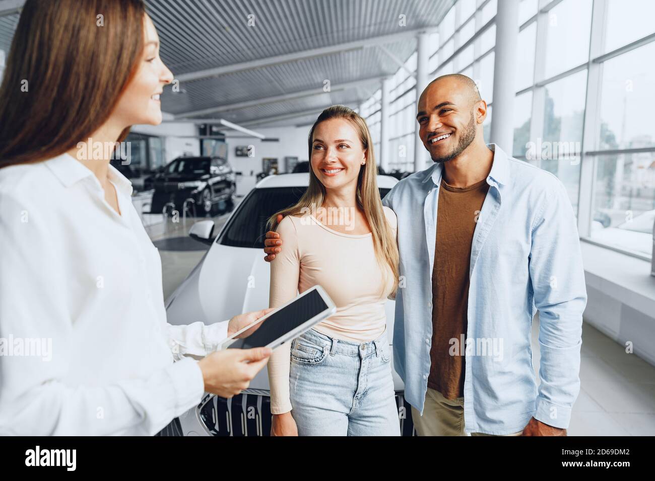 Car saleswoman in a car dealership having a talk with clients Stock ...