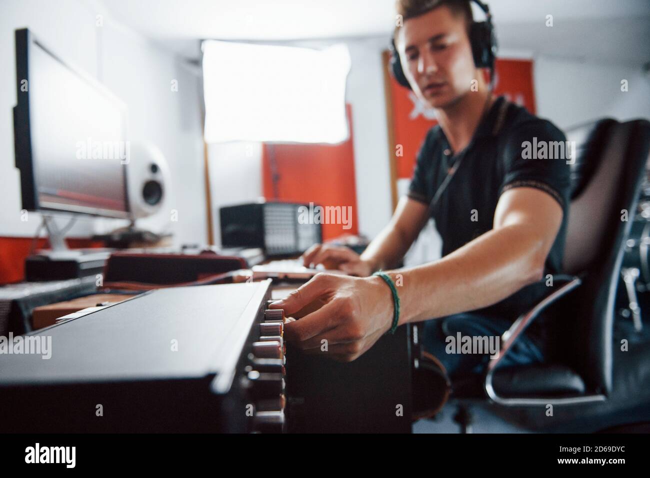 Sound engineer in headphones working and mixing music indoors in the ...