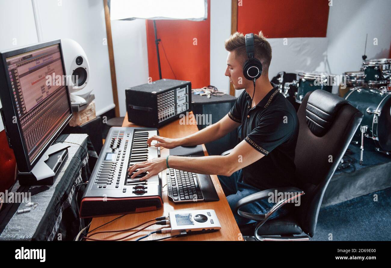 Sound engineer in headphones working and mixing music indoors in the ...