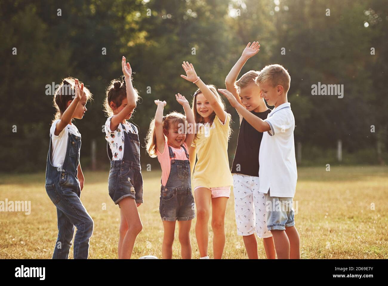 Ready for the game. Young sportive kids stands together in the field at ...