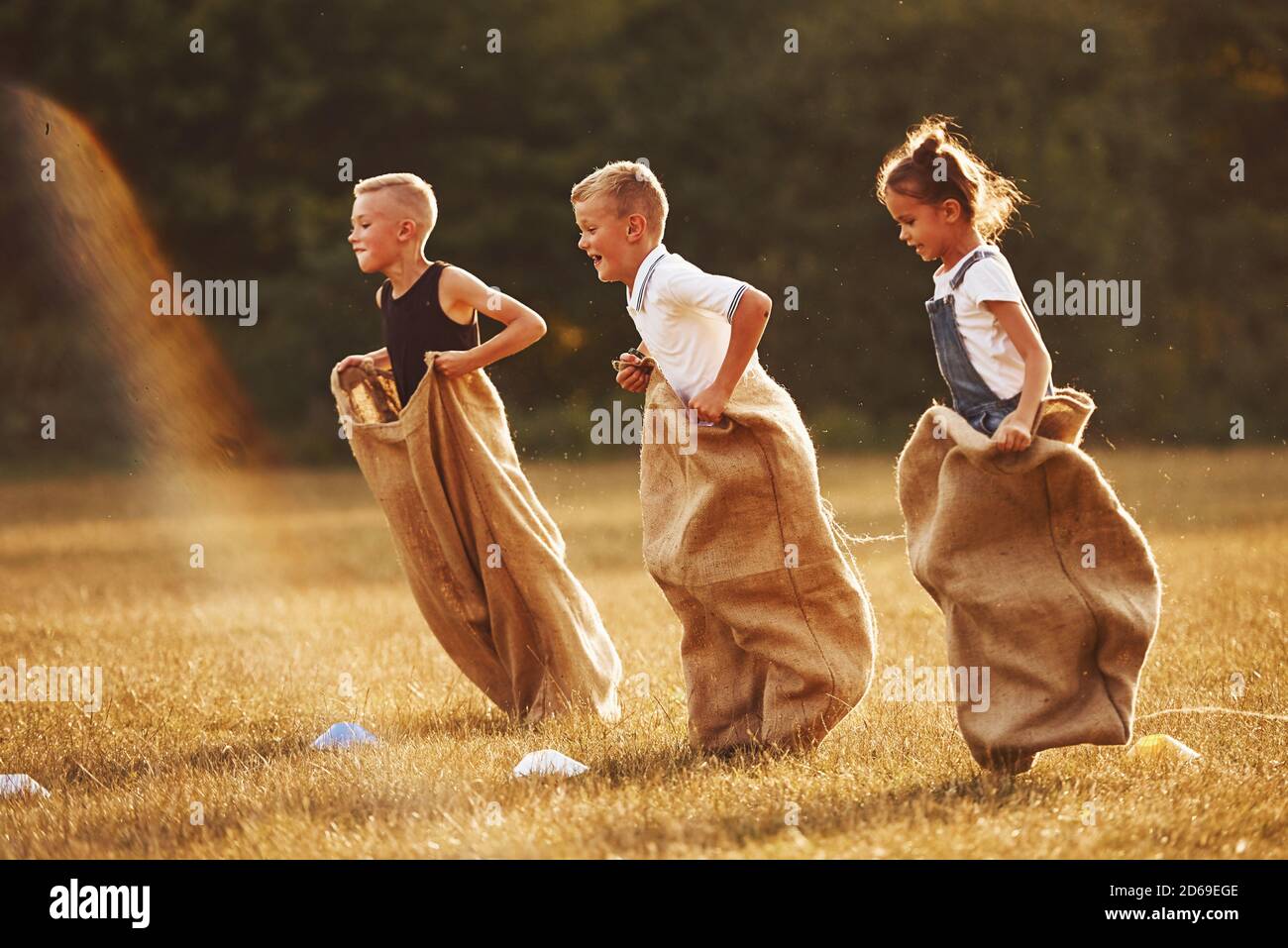 Jumping sack race outdoors in the field. Kids have fun at sunny daytime ...