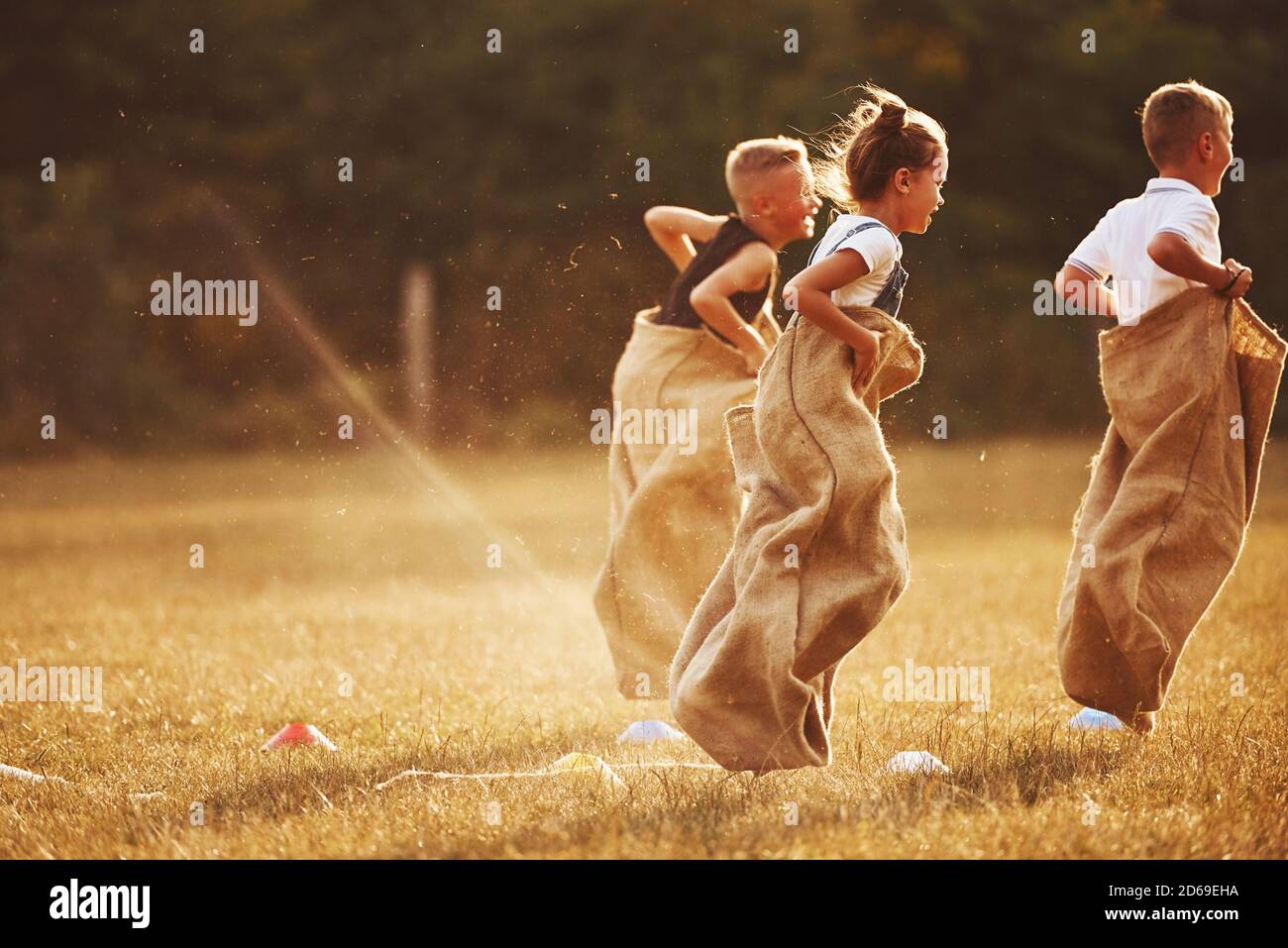 Jumping sack race outdoors in the field. Kids have fun at sunny daytime ...