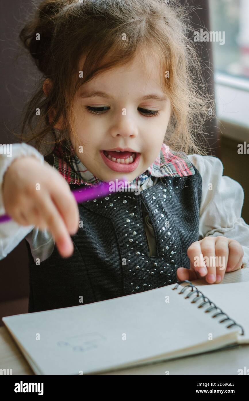 Little kid girl writing or drawing with pen in scetch book Stock Photo ...