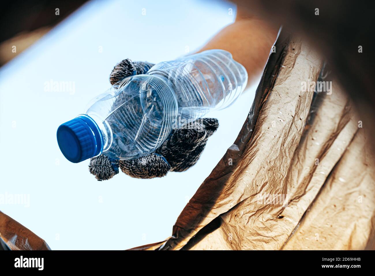Hand of a man volunteer grabbing plastic litter into a waste bag ...