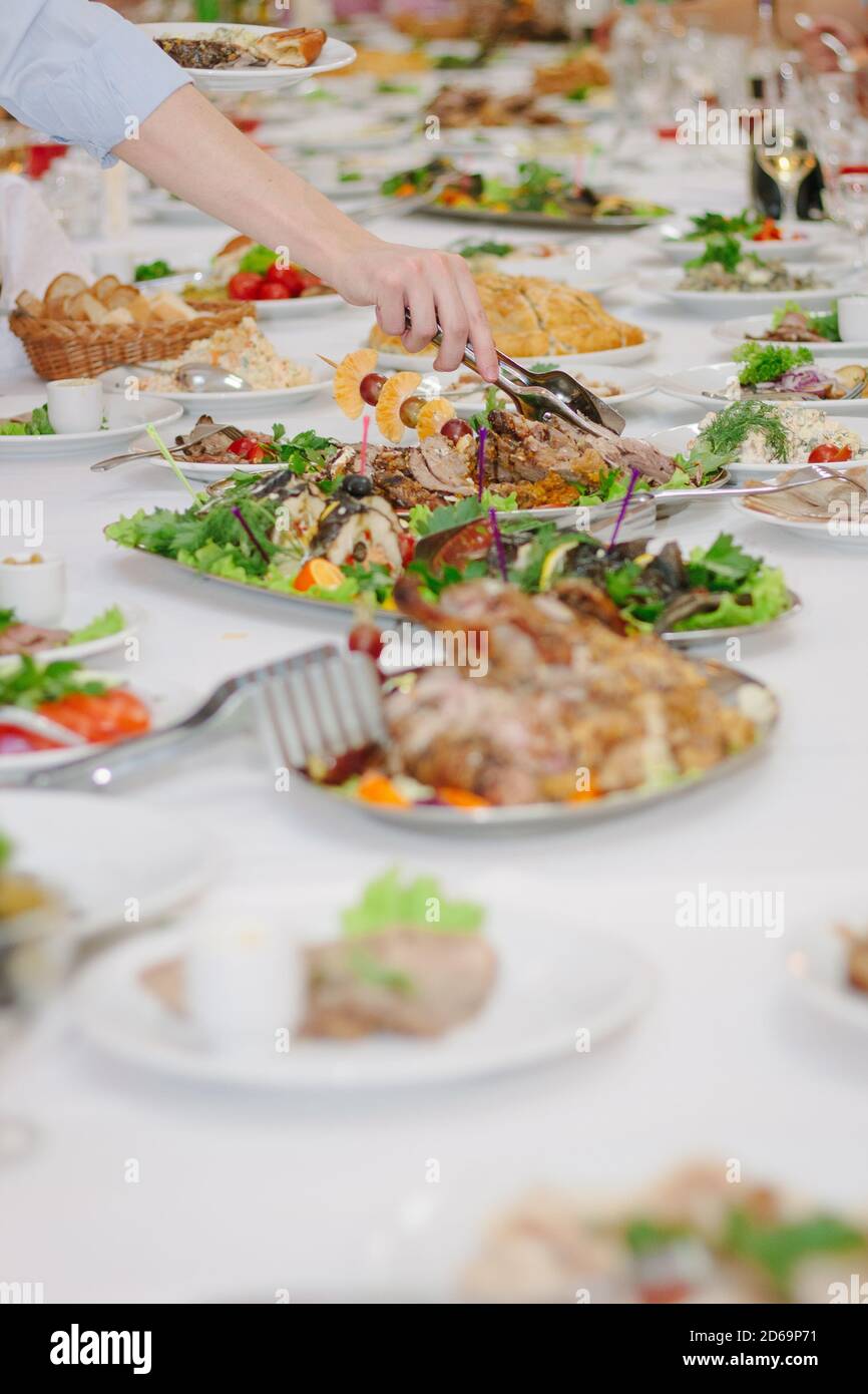 Catering table - hand with tongs taking a food Stock Photo - Alamy
