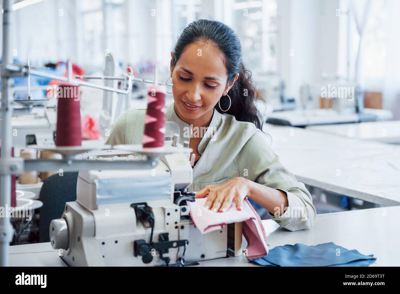Dressmaker woman sews clothes on sewing machine in factory Stock Photo ...
