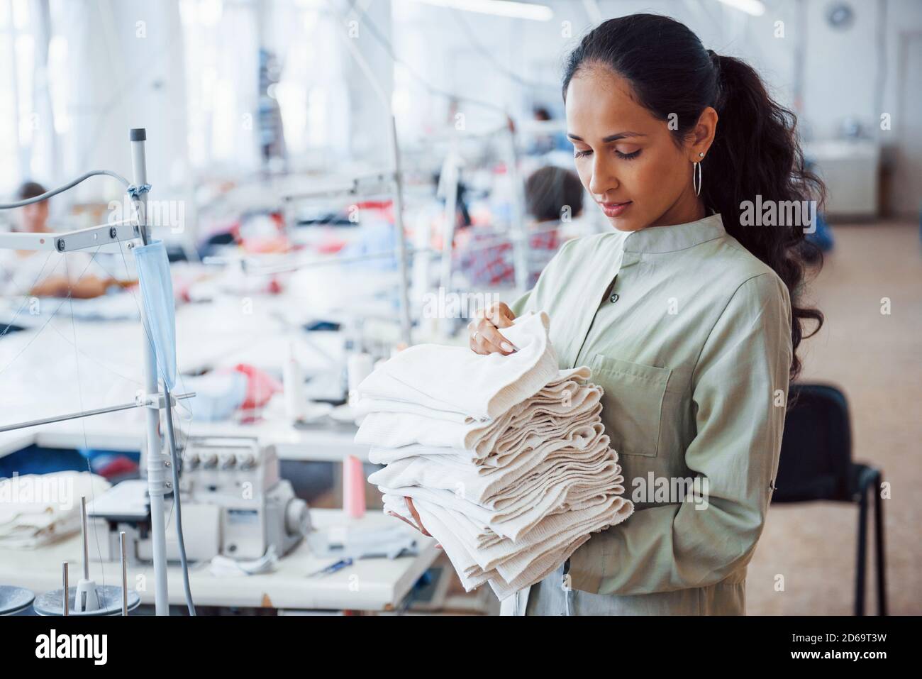 Woman dressmaker stands in the factory with cloth in hands Stock Photo ...