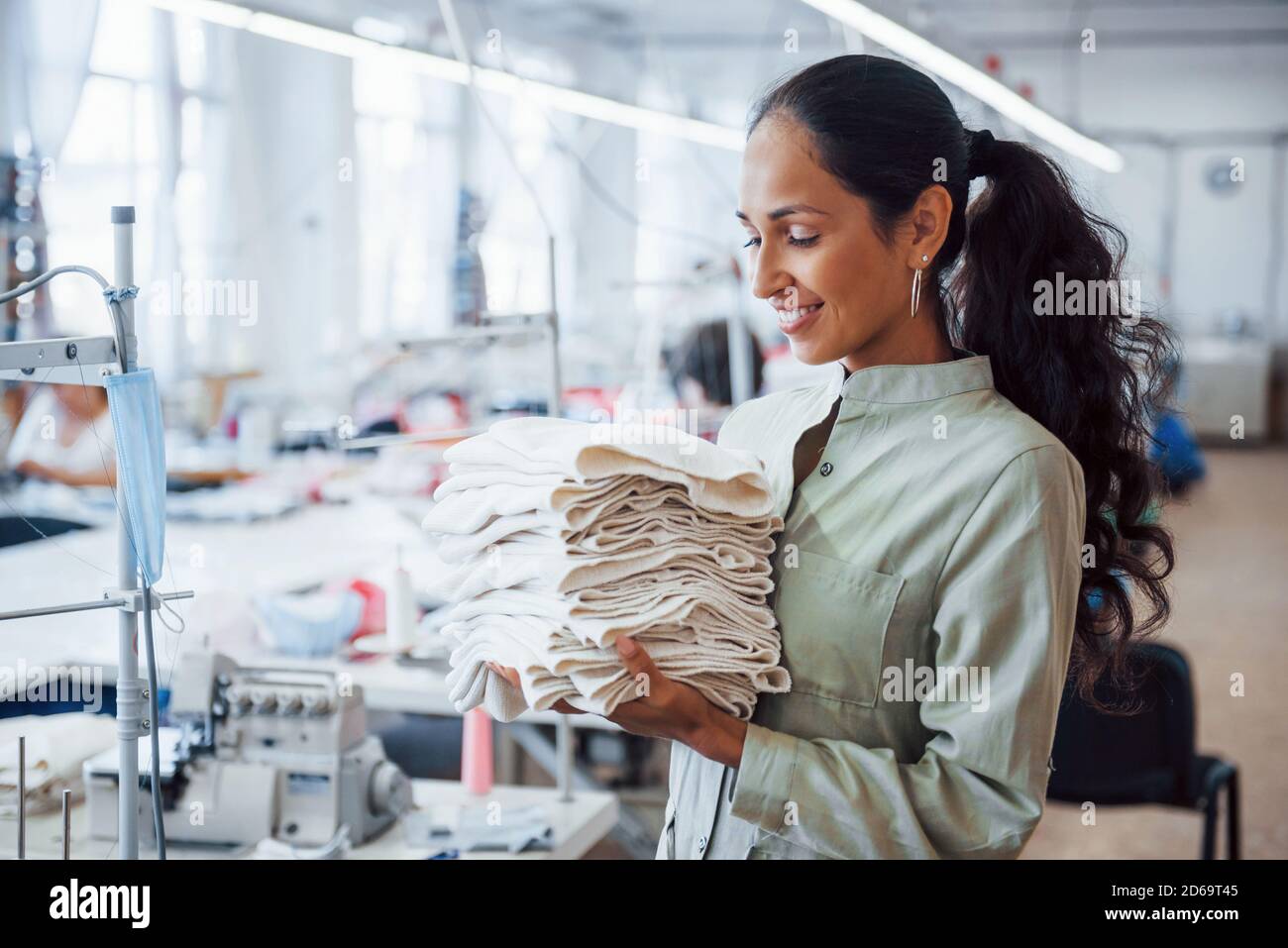 Woman dressmaker stands in the factory with cloth in hands Stock Photo ...