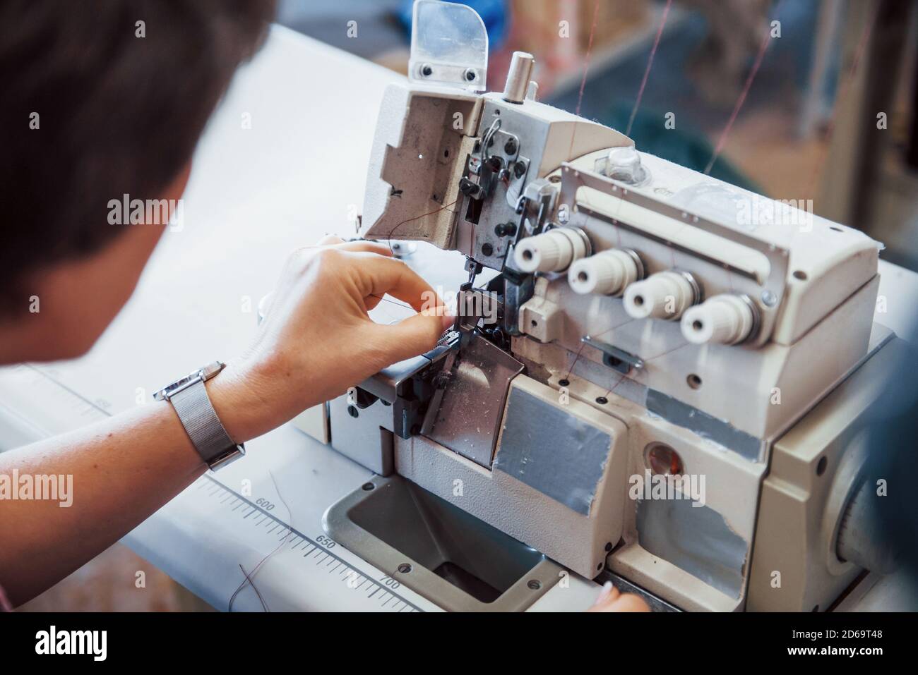 Dressmaker woman sews clothes on sewing machine in factory Stock Photo ...