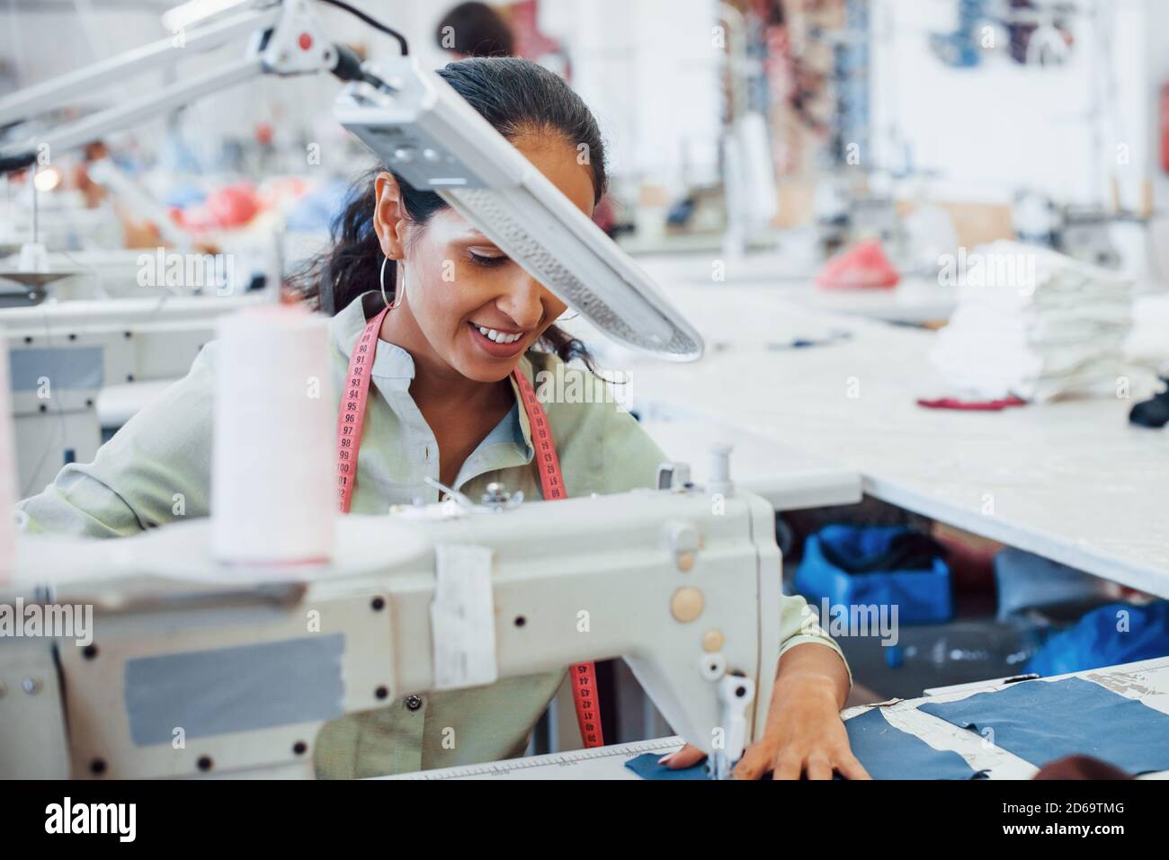 Dressmaker woman sews clothes on sewing machine in factory Stock Photo ...