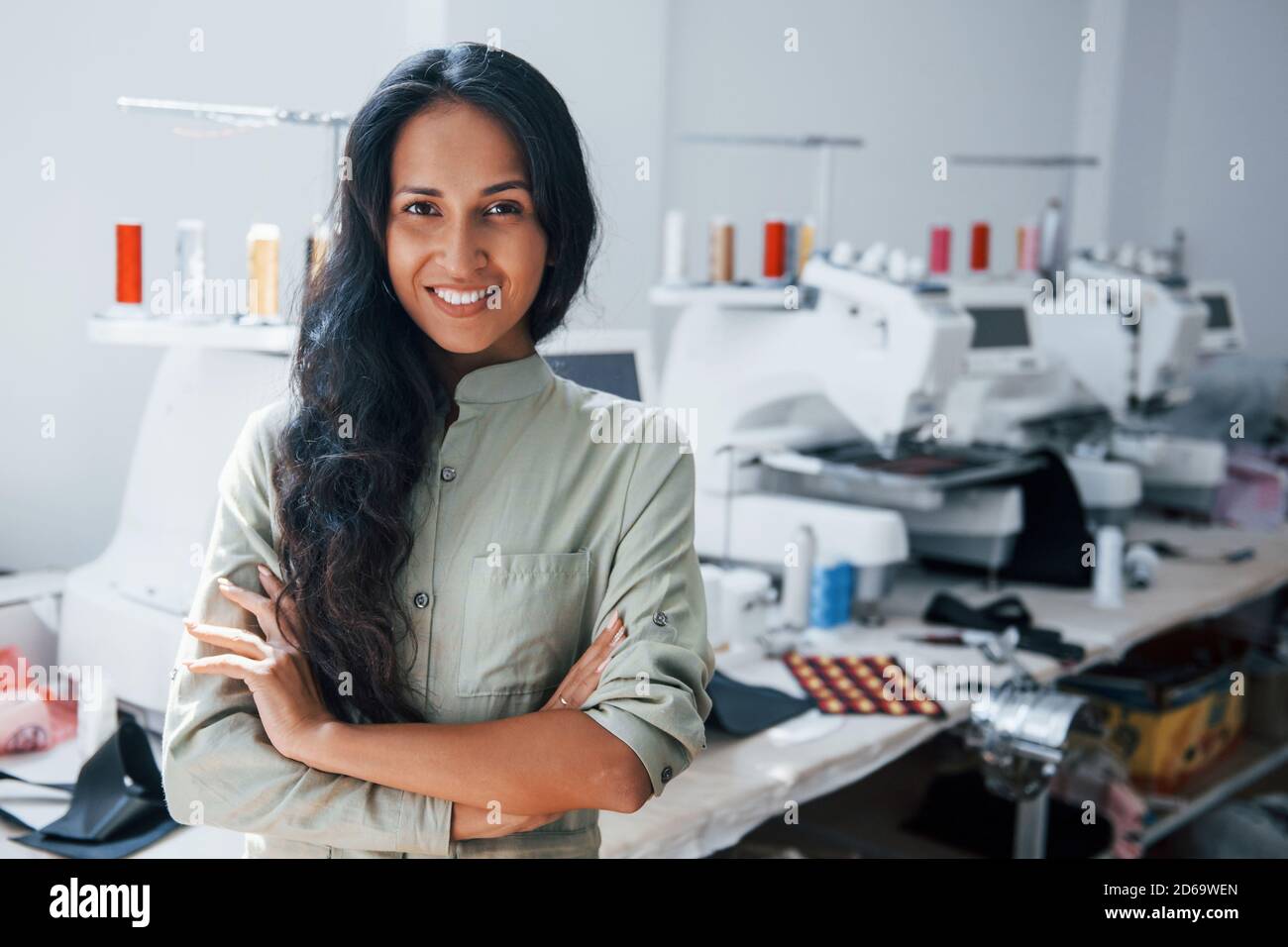 With arms crossed. Beautiful female worker is in the sewing factory ...