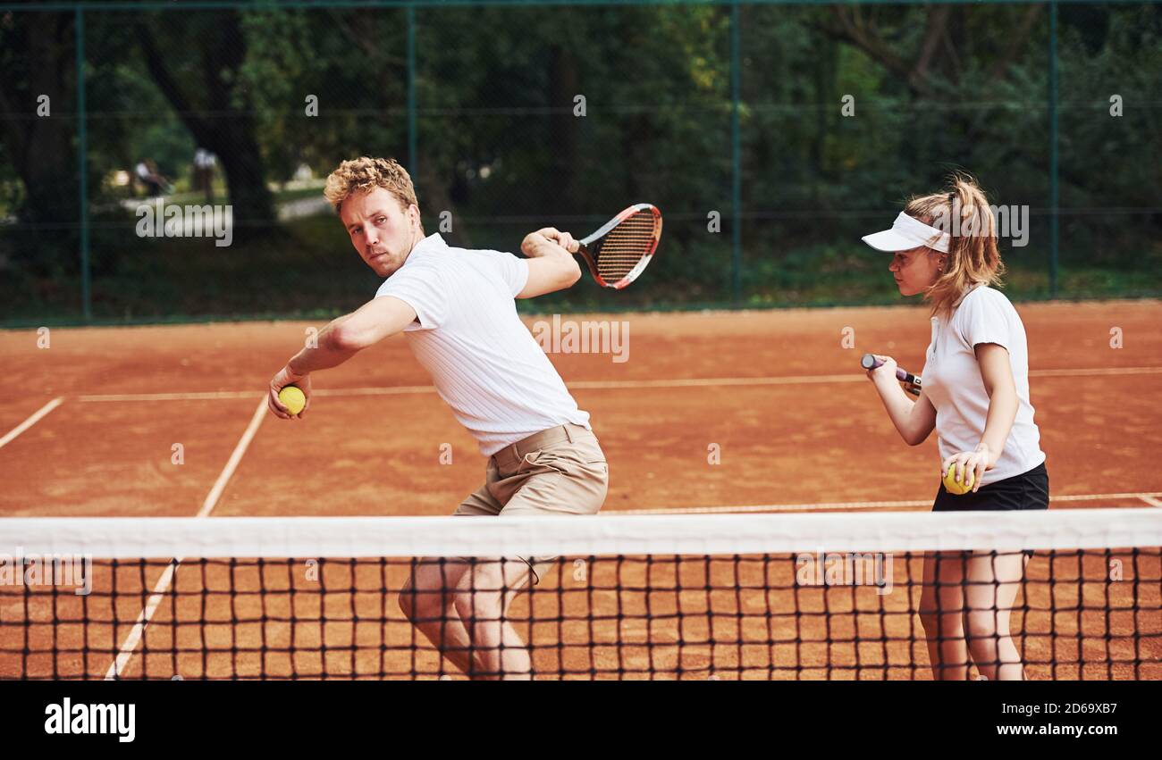 Two people in sport uniform plays tennis together on the court Stock ...