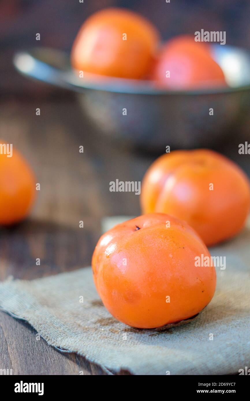 Group of persimmons on wooden table and piece of fabric Stock Photo - Alamy
