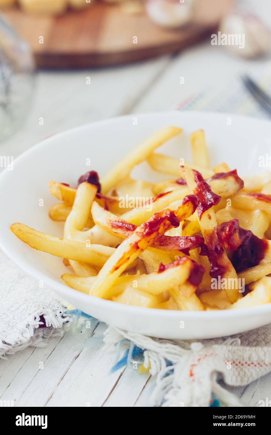 Poutine fries with tomato sauce and cheese on white table Stock Photo ...