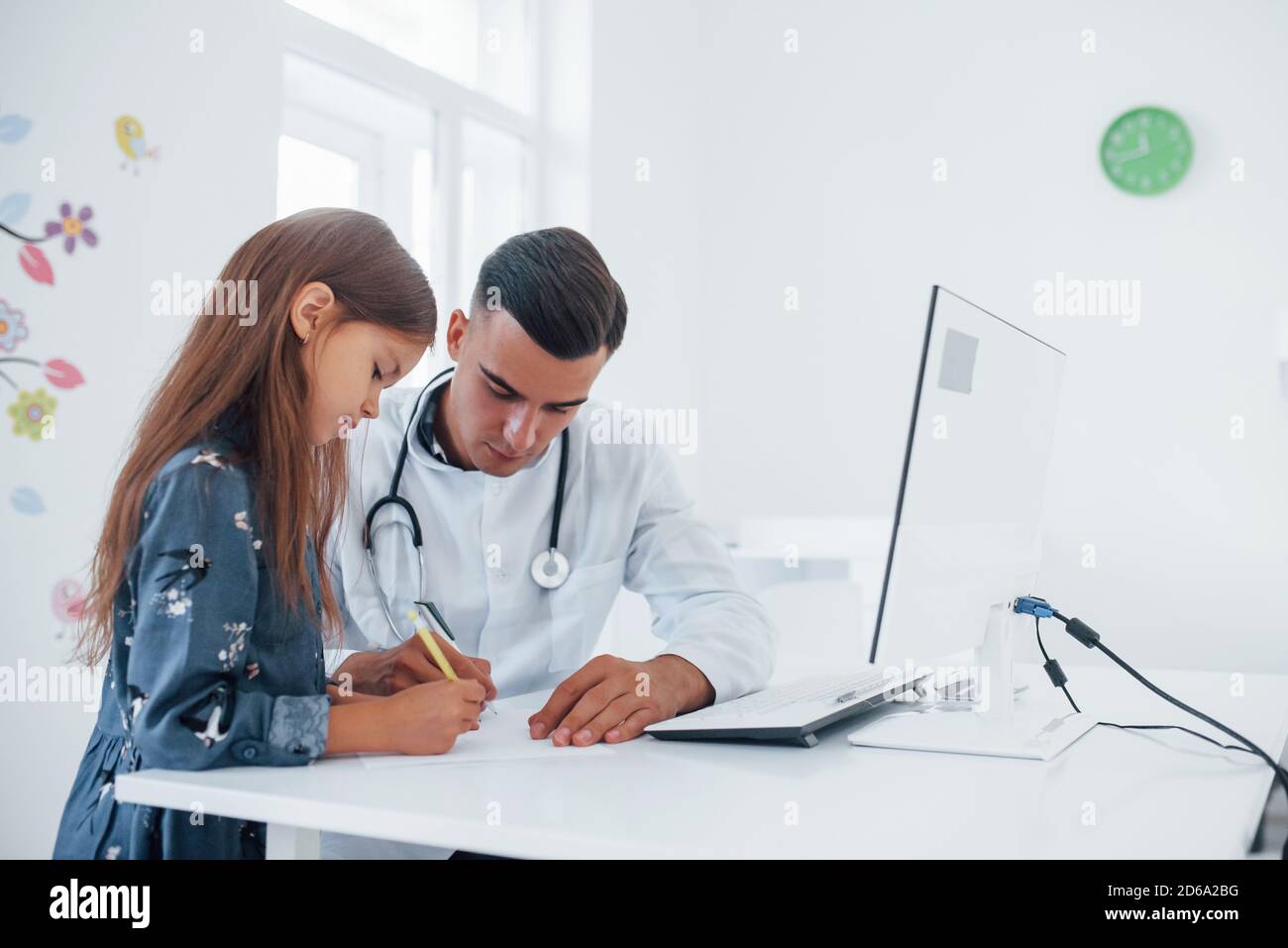 Works with documents. Young pediatrician works with little female ...