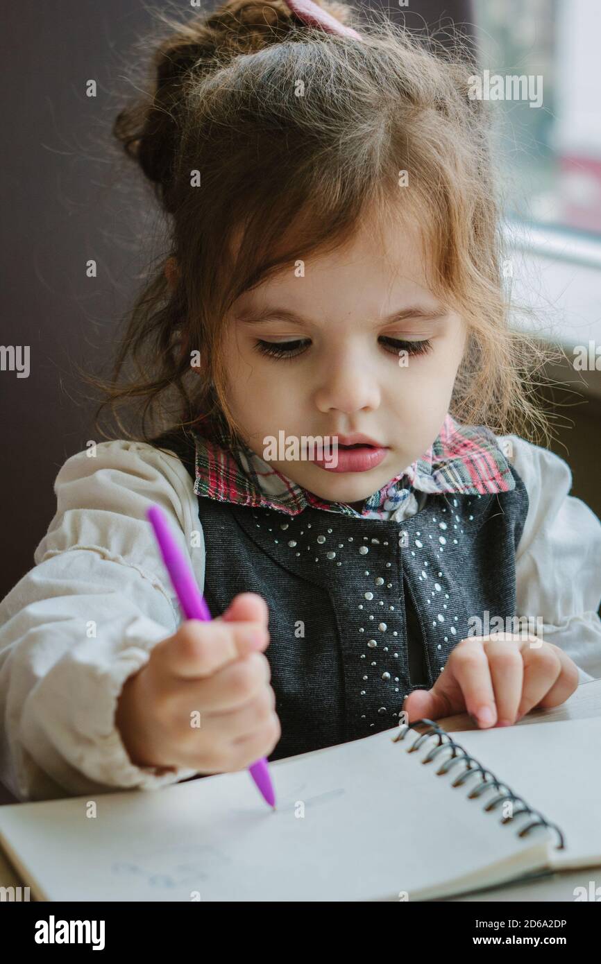 Little kid girl writing or drawing with pen in scetch book Stock Photo ...