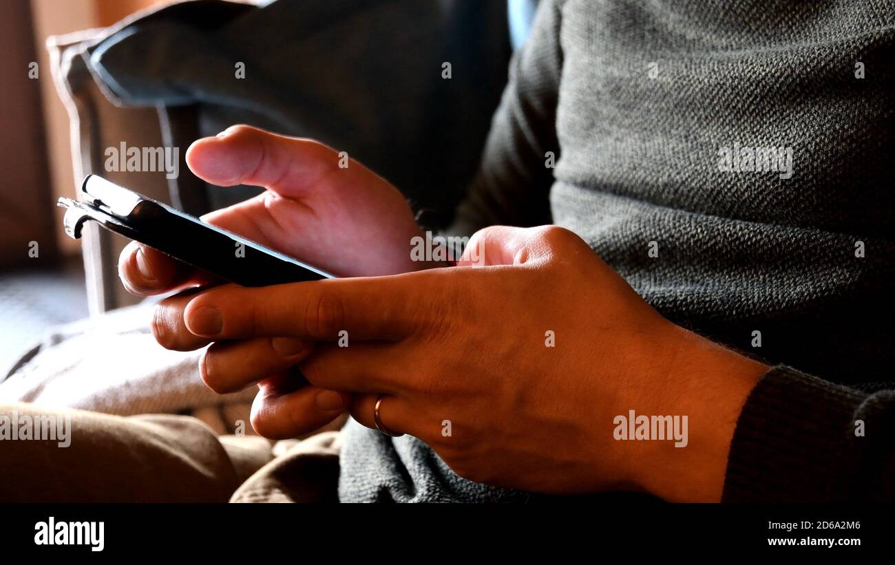 Young adult man hands tapping and swiping his phone closeup. User ...