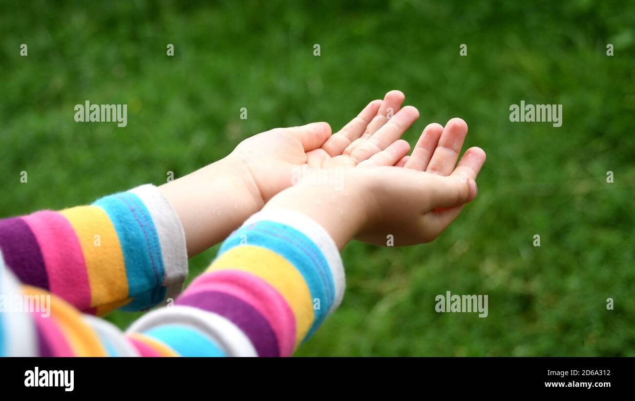 Closeup of wet hands of baby girl in colorful striped sleeve shirt ...