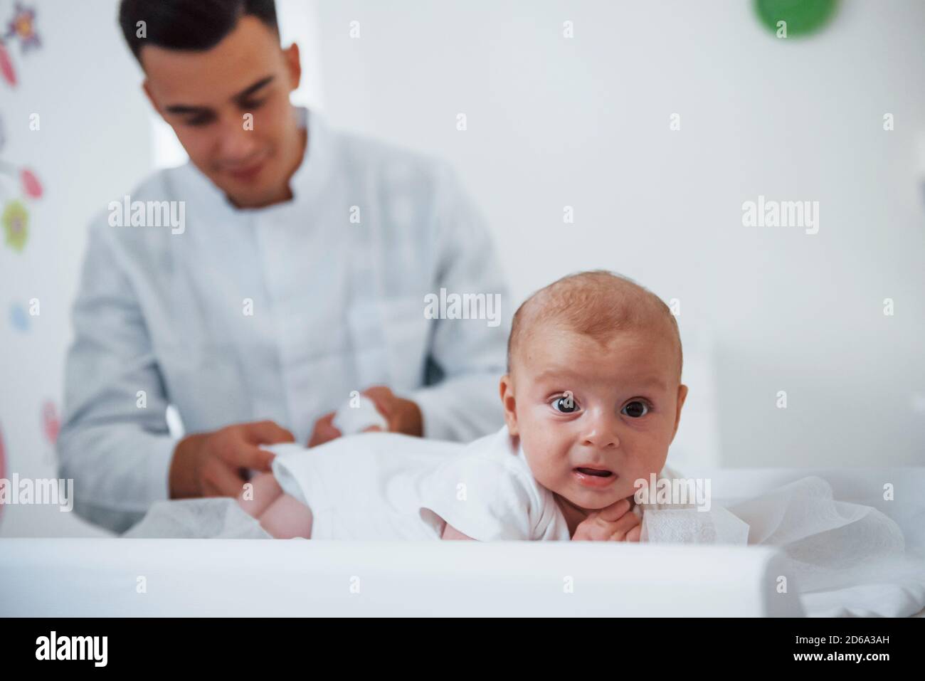 Little baby lying on the table. Young pediatrician is in the clinic at ...