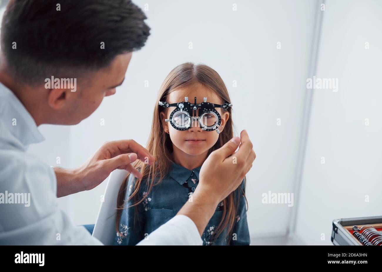 Testing vision. Young ophthalmologist is with little female visitor in ...