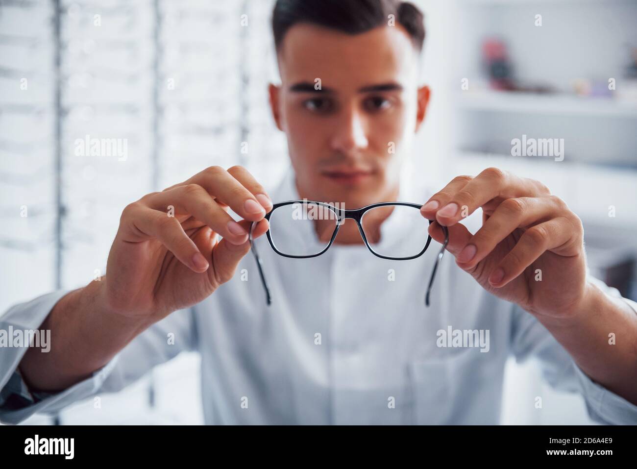 Focused photo of brand new glasses that holds by the young oculist ...