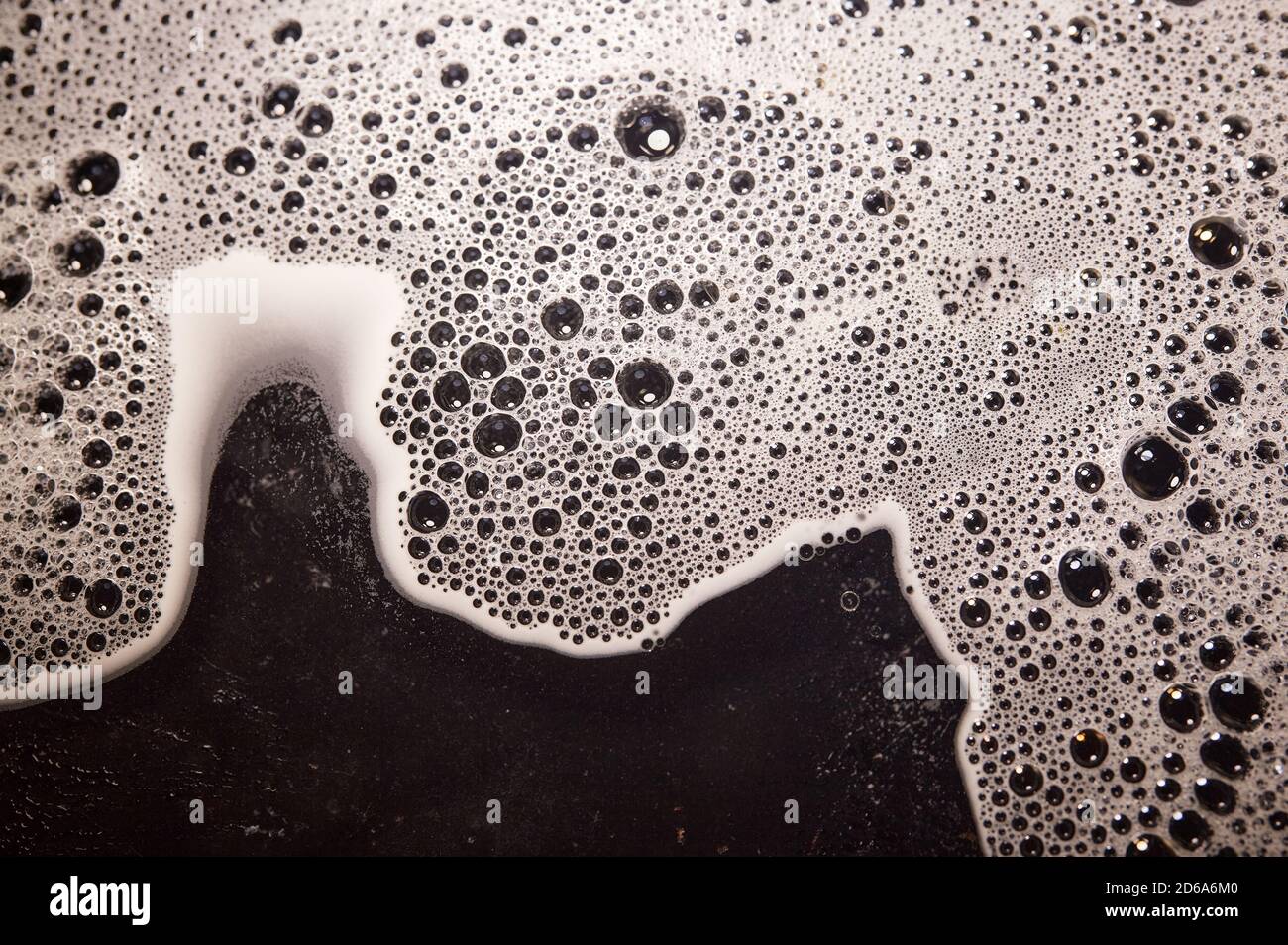 Close-up crop fragment of a pan's surface covered with the dishwashing ...