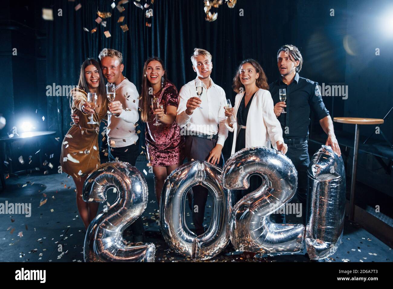 Cheerful group of people with drinks and balloons in hands celebrating ...