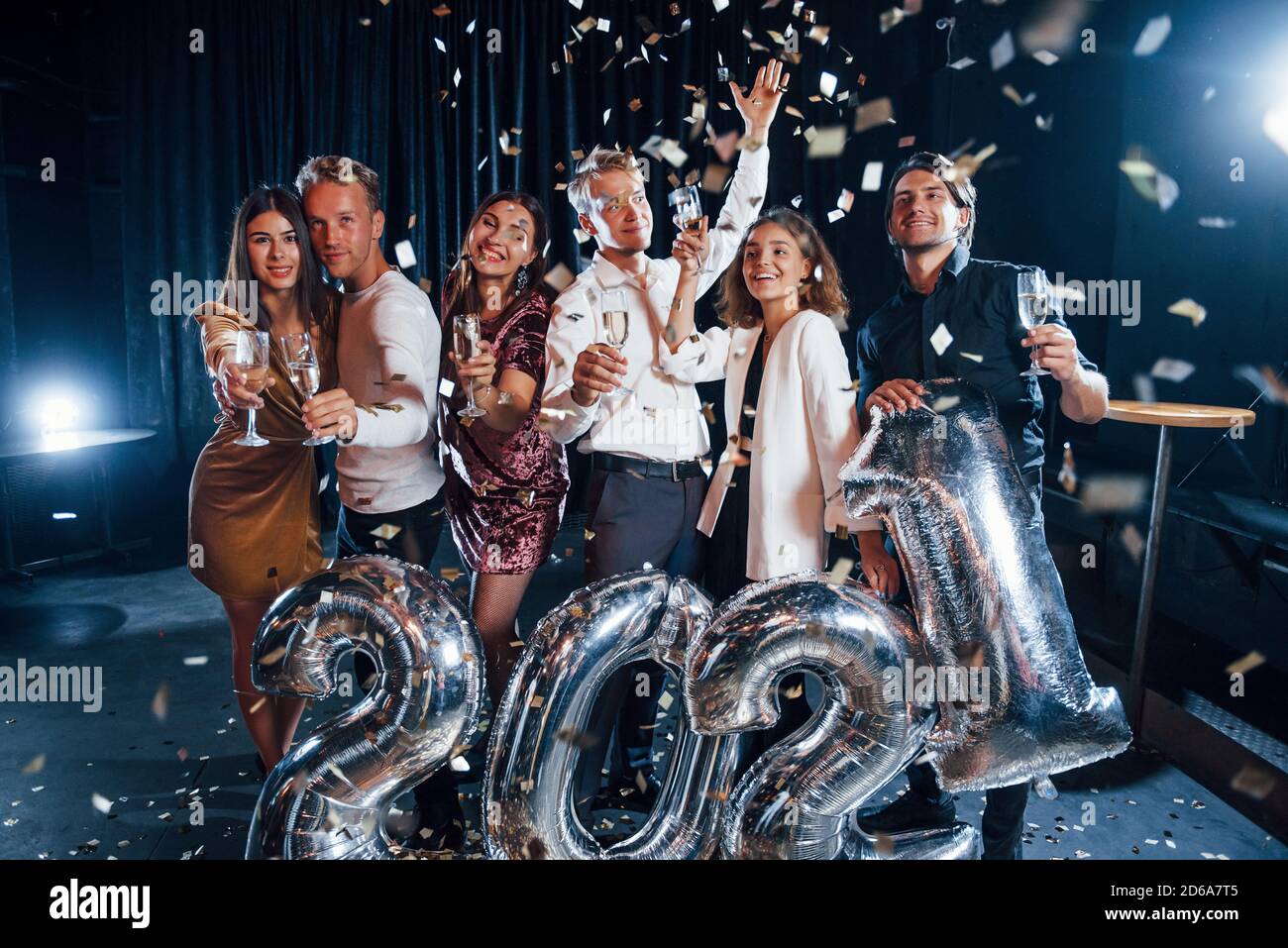 Confetti is in the air. Cheerful group of people with drinks and ...