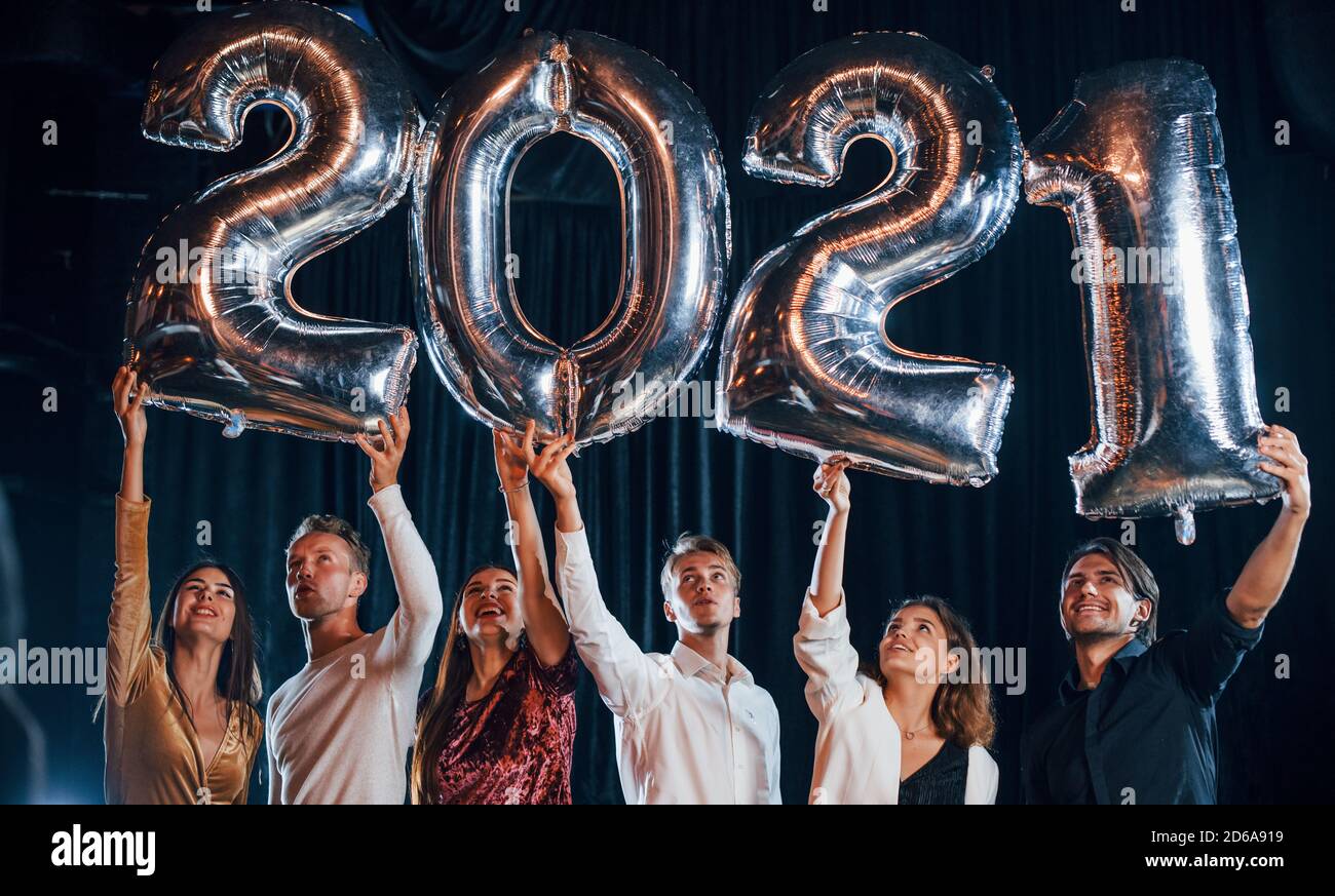 Cheerful group of people with drinks and balloons in hands celebrating ...